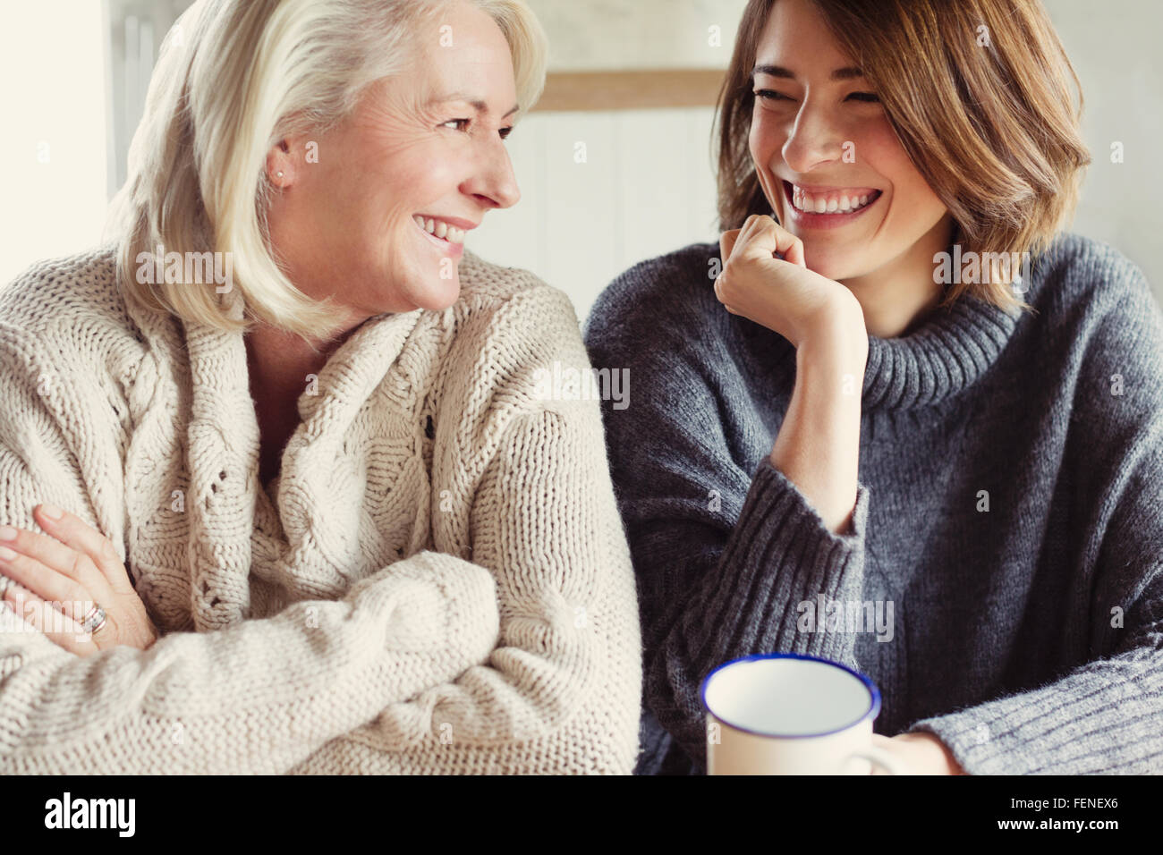 Laughing mother and daughter in sweaters drinking coffee Stock Photo ...