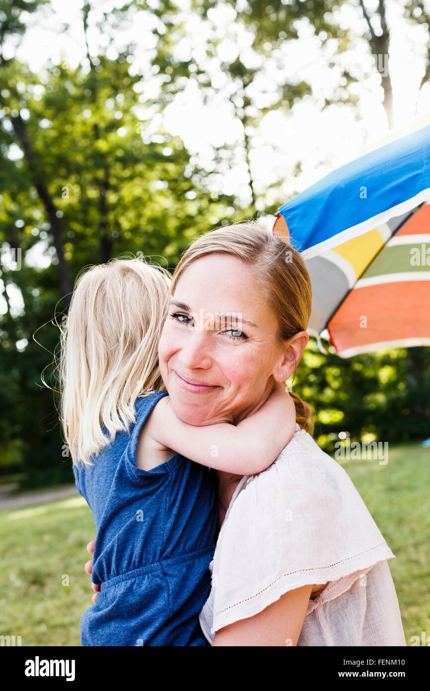 Portrait of mid adult woman and toddler daughter hugging in park Stock ...