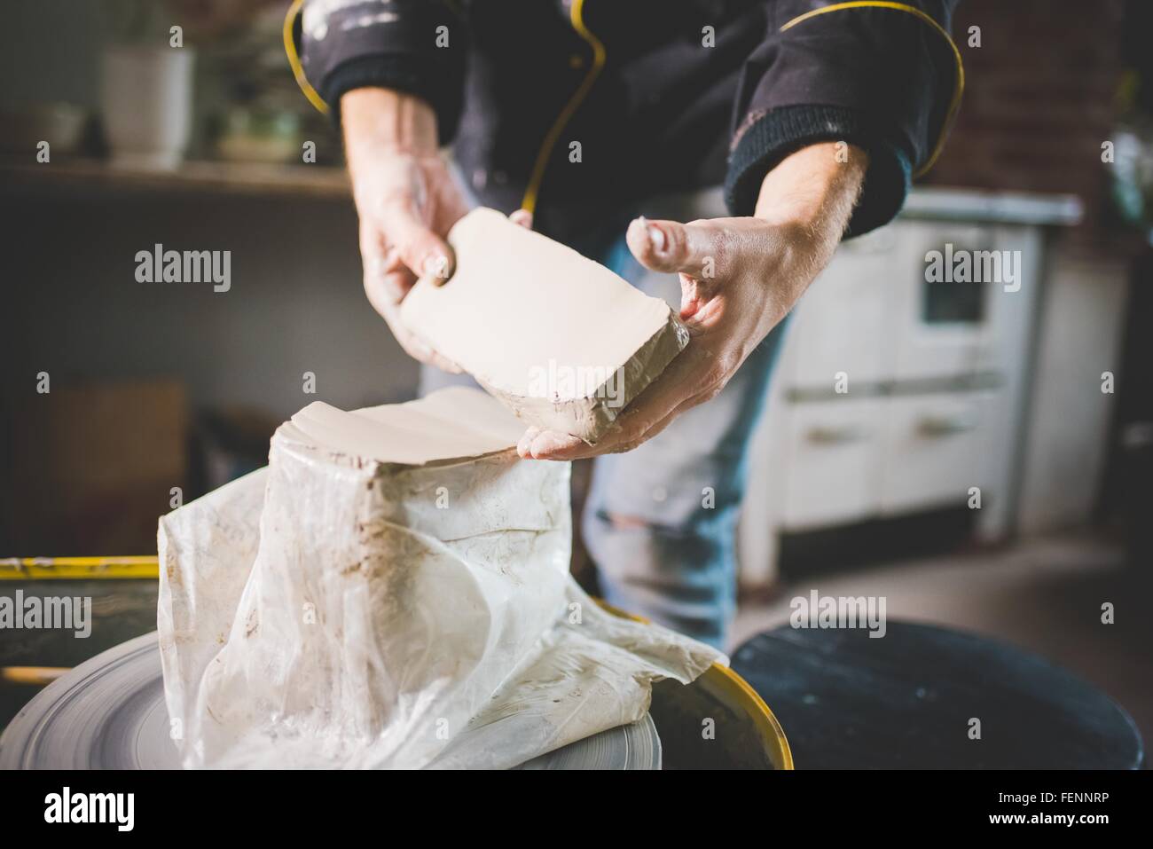 Cropped view of mid adult mans hands removing clay block from plastic ...
