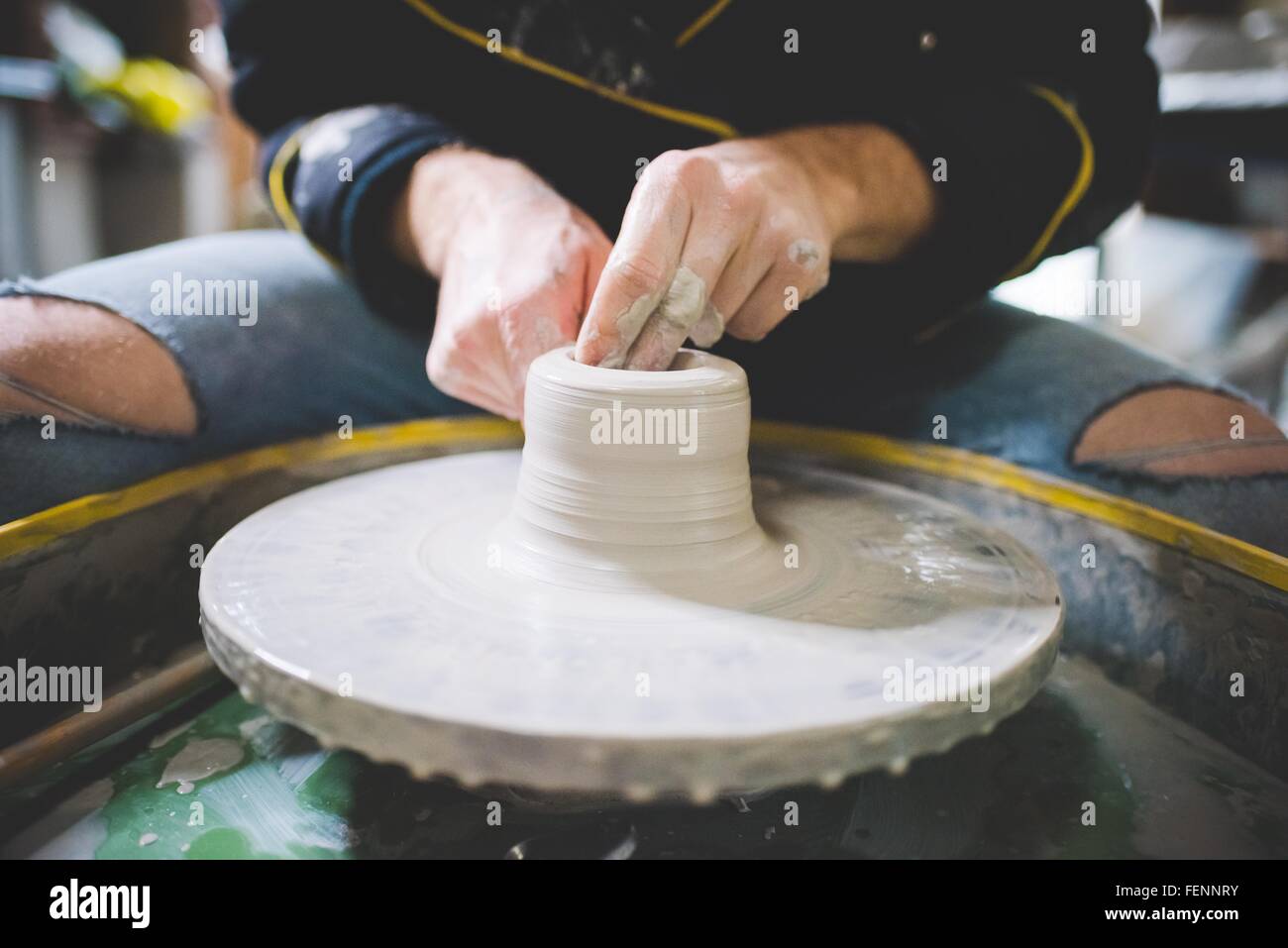 Cropped front view of mid adult man making clay on pottery wheel Stock ...