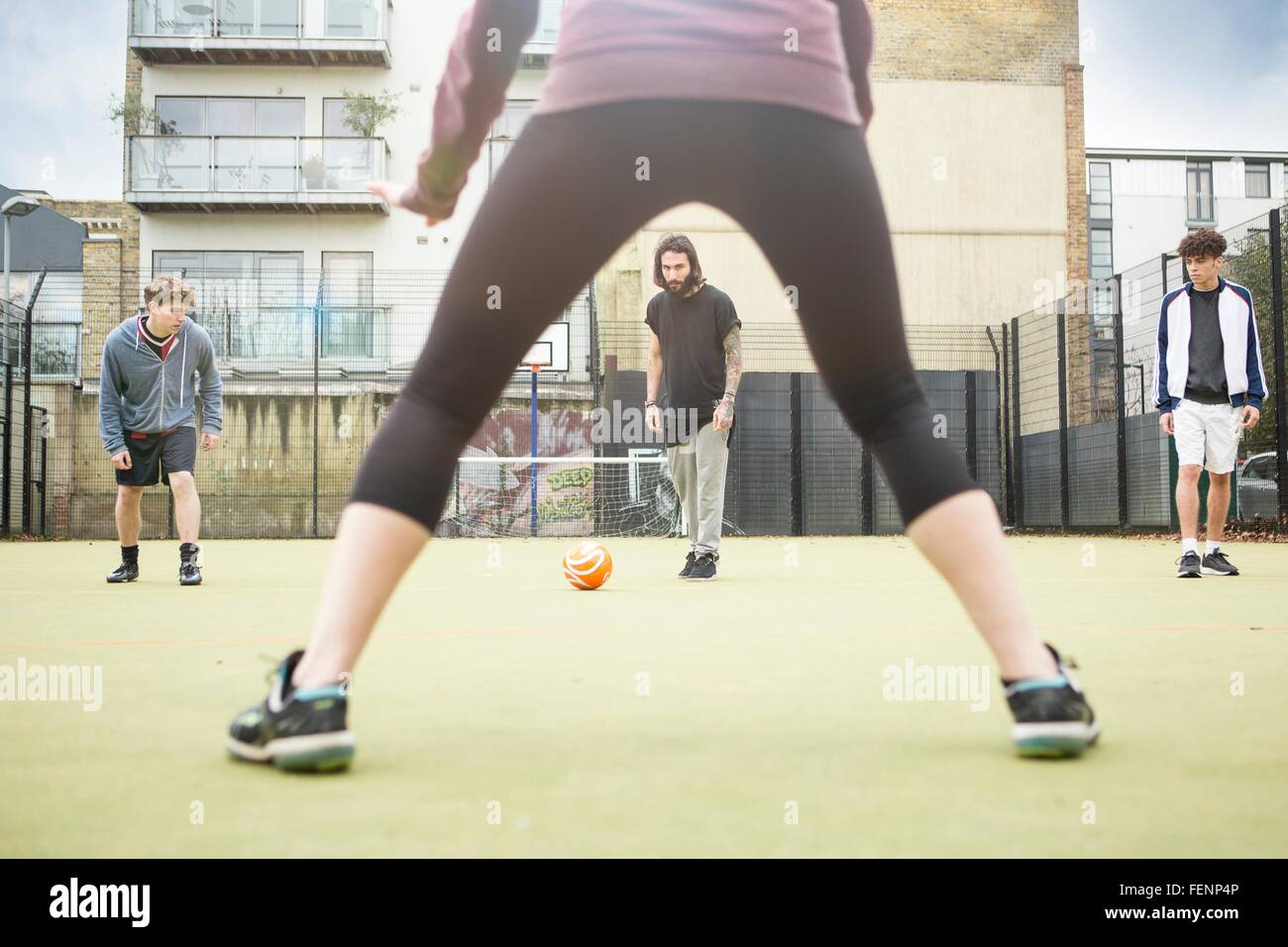 Group of adults playing football on urban football pitch Stock Photo ...