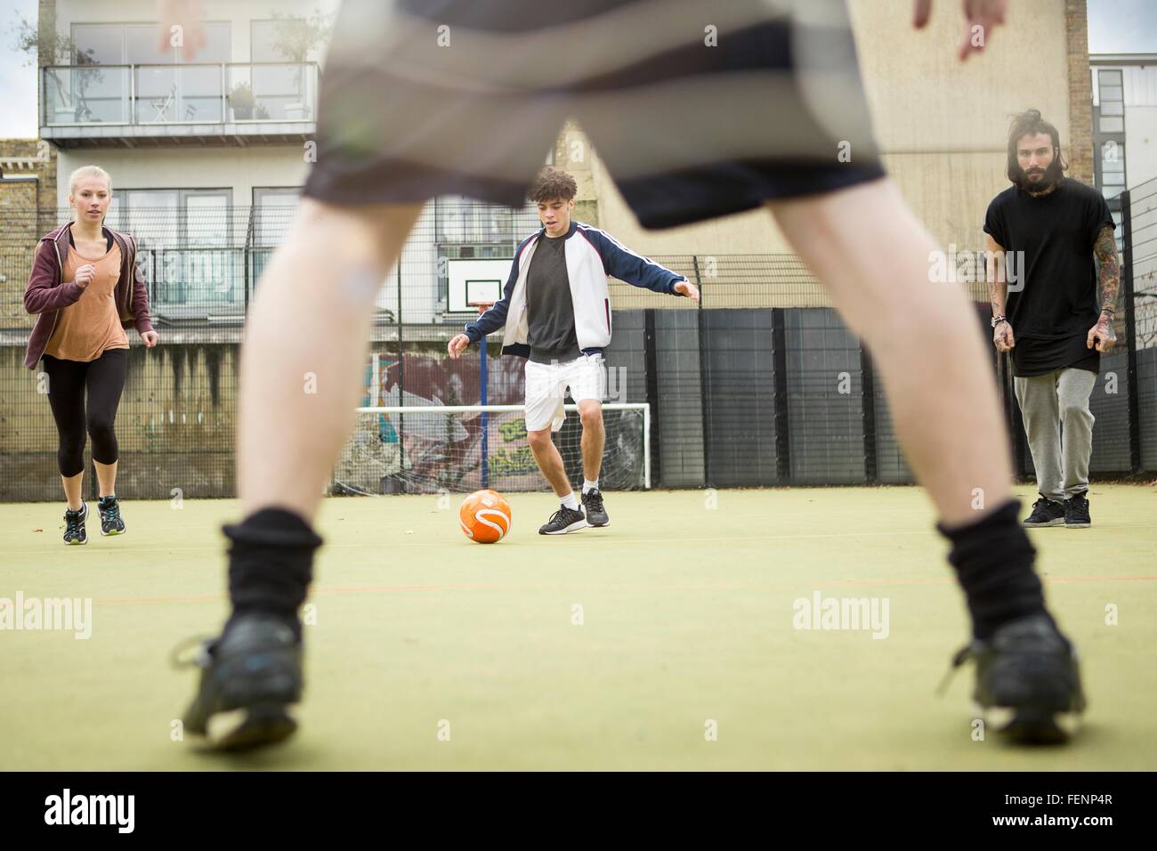 Group of adults playing football on urban football pitch Stock Photo ...