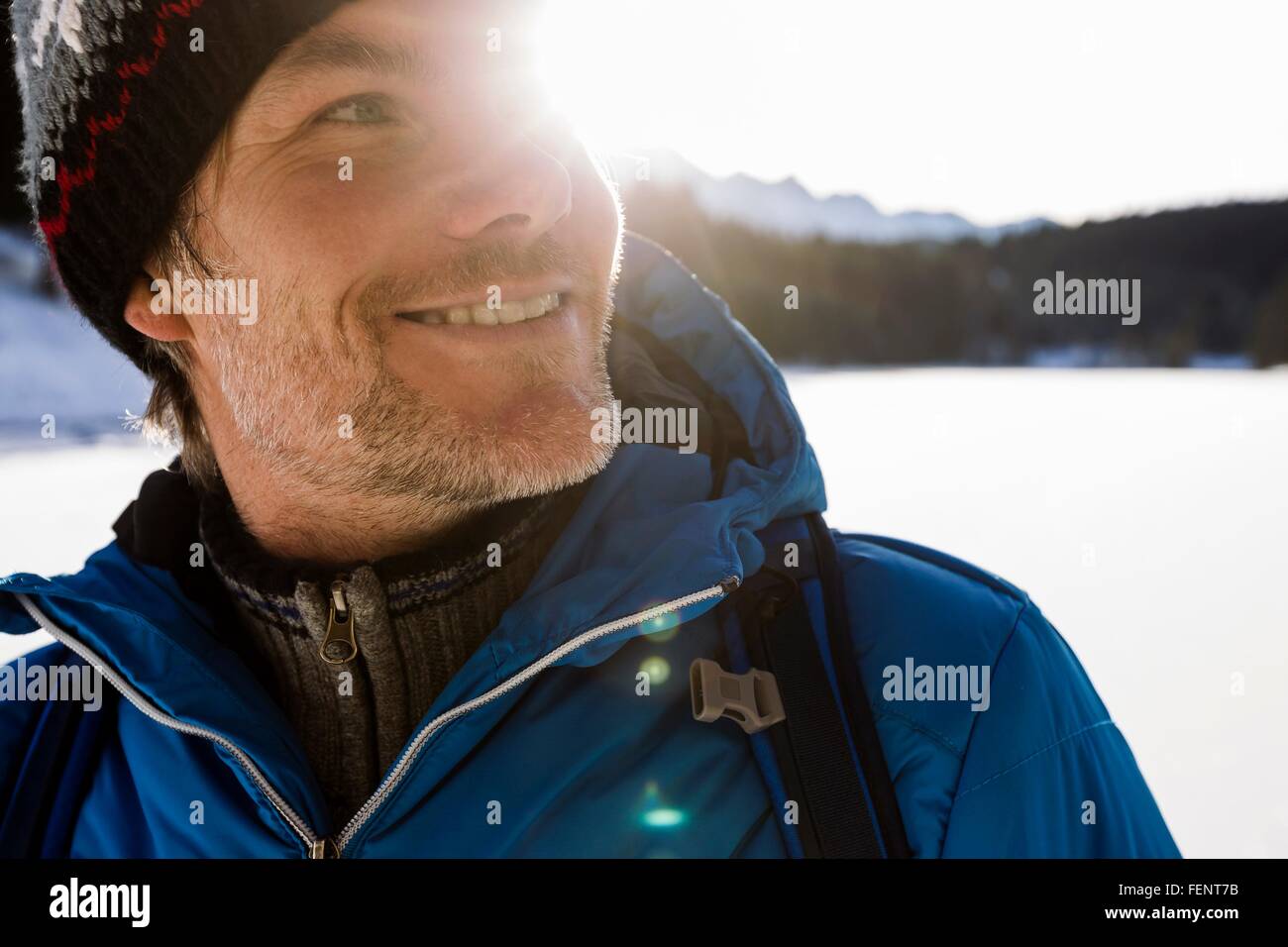 Close up sunlit portrait of mature man hiking in snow covered landscape ...