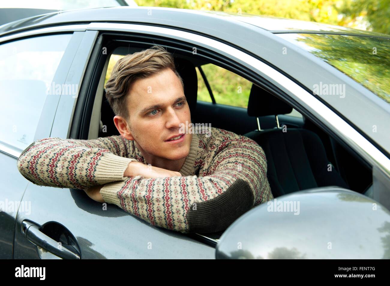 Young man leaning and looking out from car window Stock Photo - Alamy