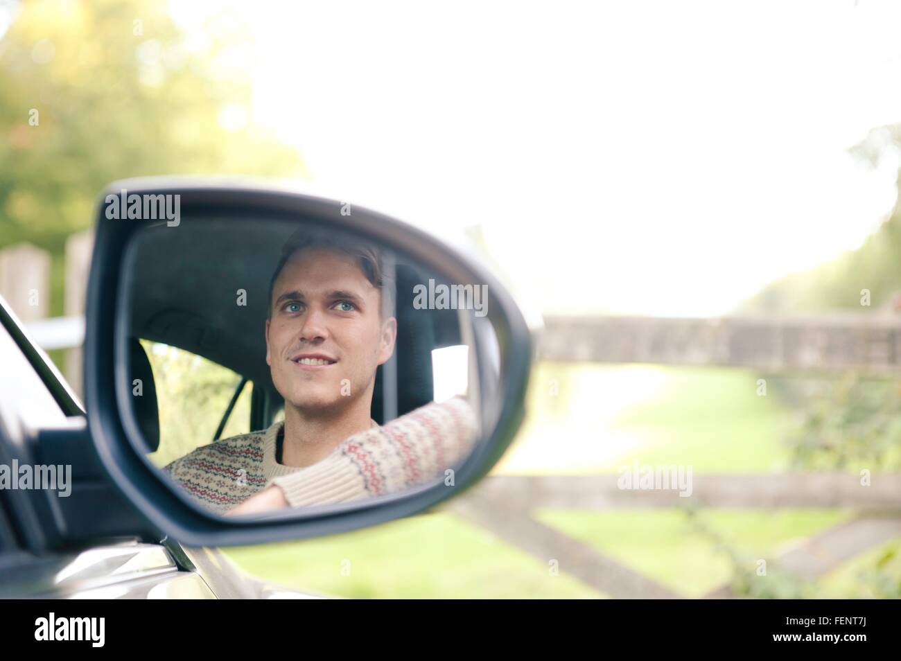 Wing mirror reflection of young man in car parked at rural gate Stock ...
