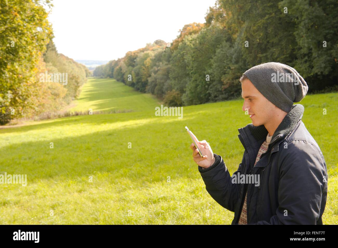 Young man in field reading smartphone texts, Great Missenden ...