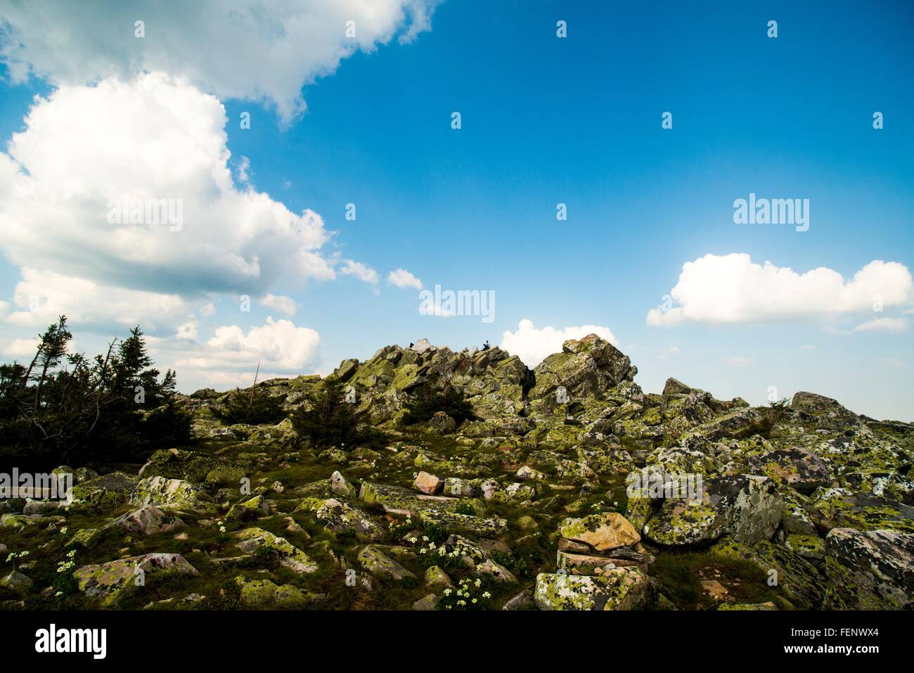 Male hikers sitting on distant rocks in rugged landscape, Russia Stock ...