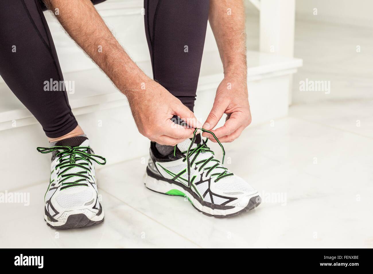 Cropped shot of senior mans hands tying trainer laces on staircase ...