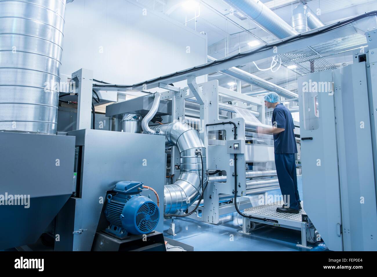 Worker operating printing machine in food packaging printing factory ...