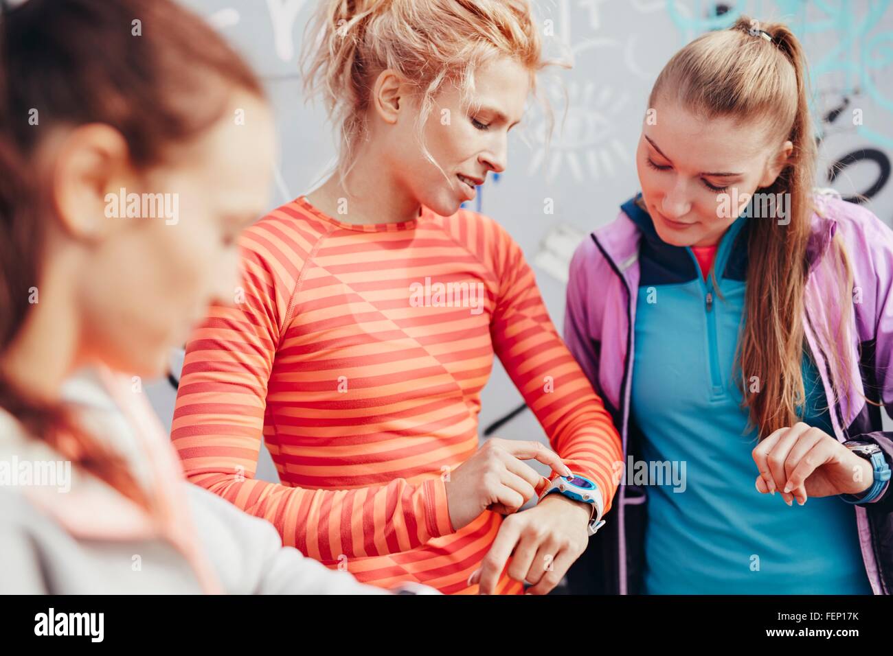 Three female runners checking time on smartwatch Stock Photo - Alamy