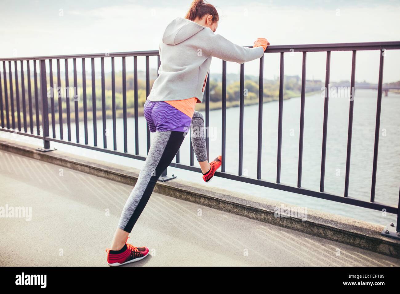 Female runner doing warm up exercise on footbridge Stock Photo - Alamy