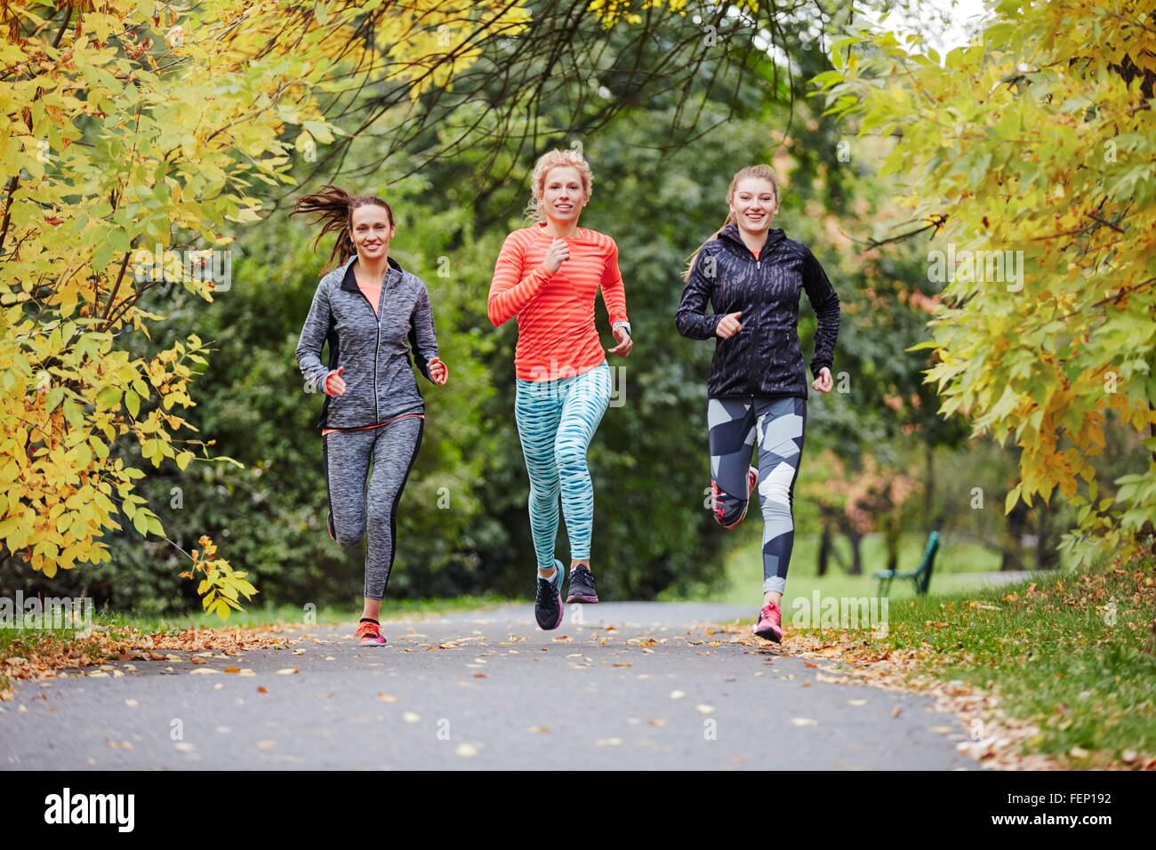 Three female runners running along park path Stock Photo - Alamy