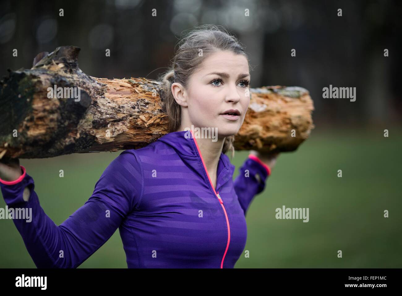 Young woman carrying tree branch on shoulder looking away Stock Photo ...