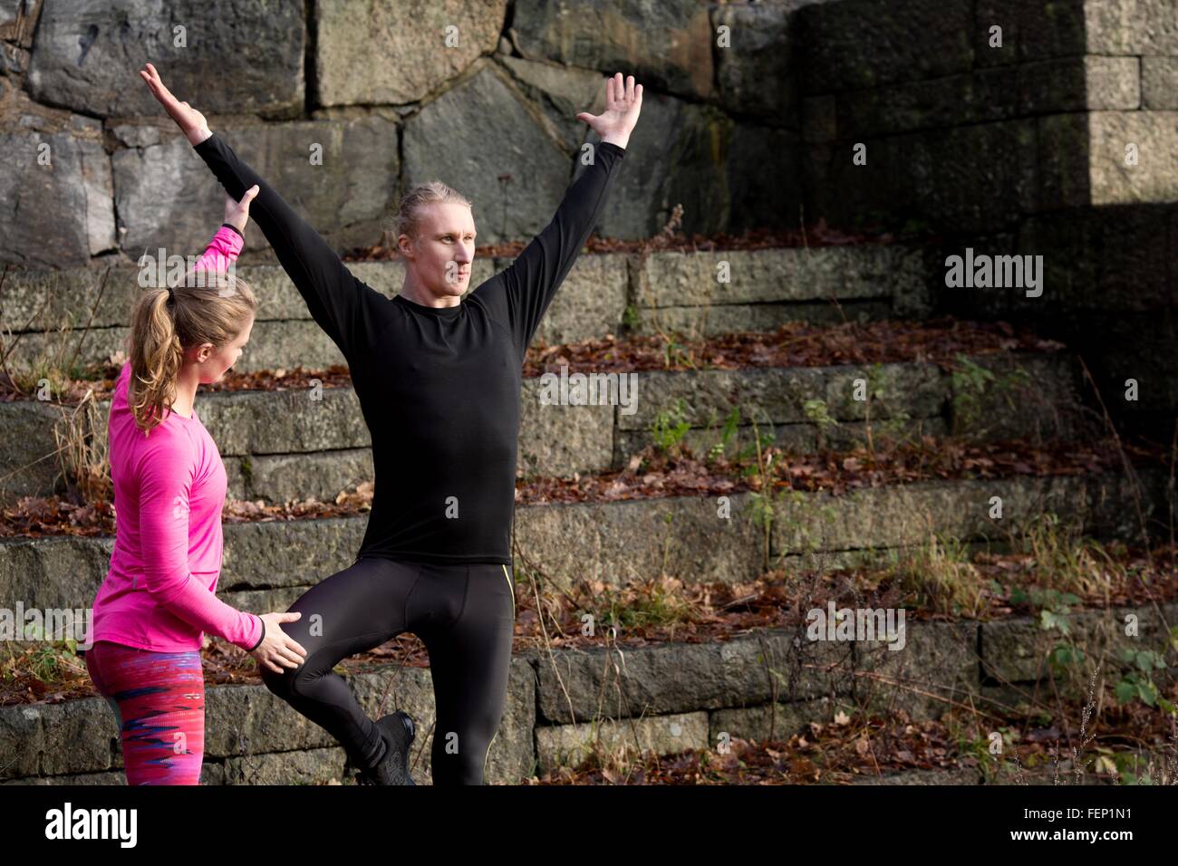 Mid adult man on stone steps arms raised standing on one leg, young ...