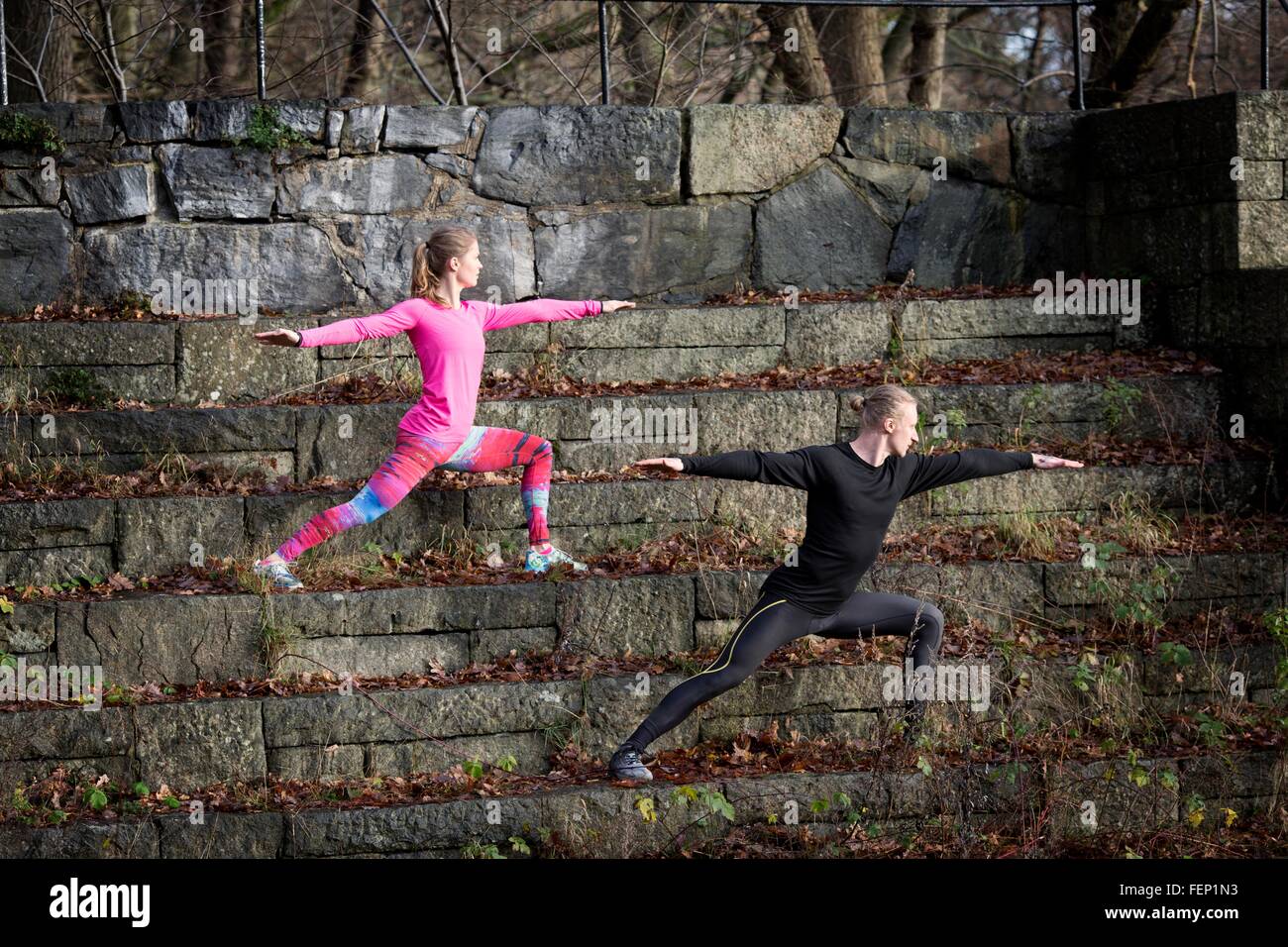 Couple on stone steps in lunge stance arms open stretching, looking ...