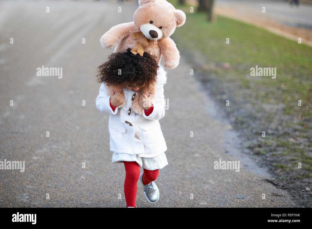 Front view of girl carrying soft toy on shoulders looking down Stock ...
