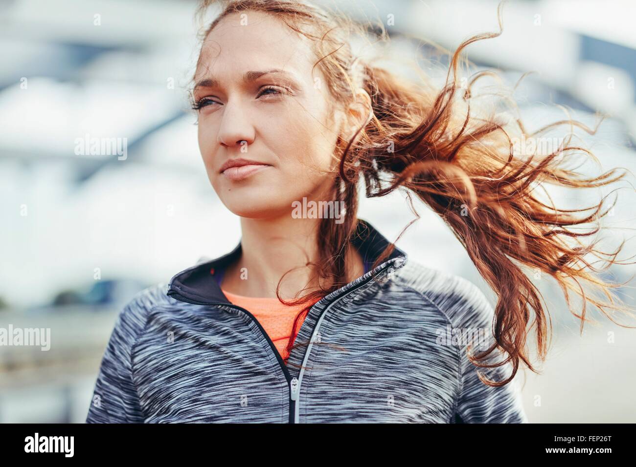 Portrait of female runner with flyaway hair on city footbridge Stock ...