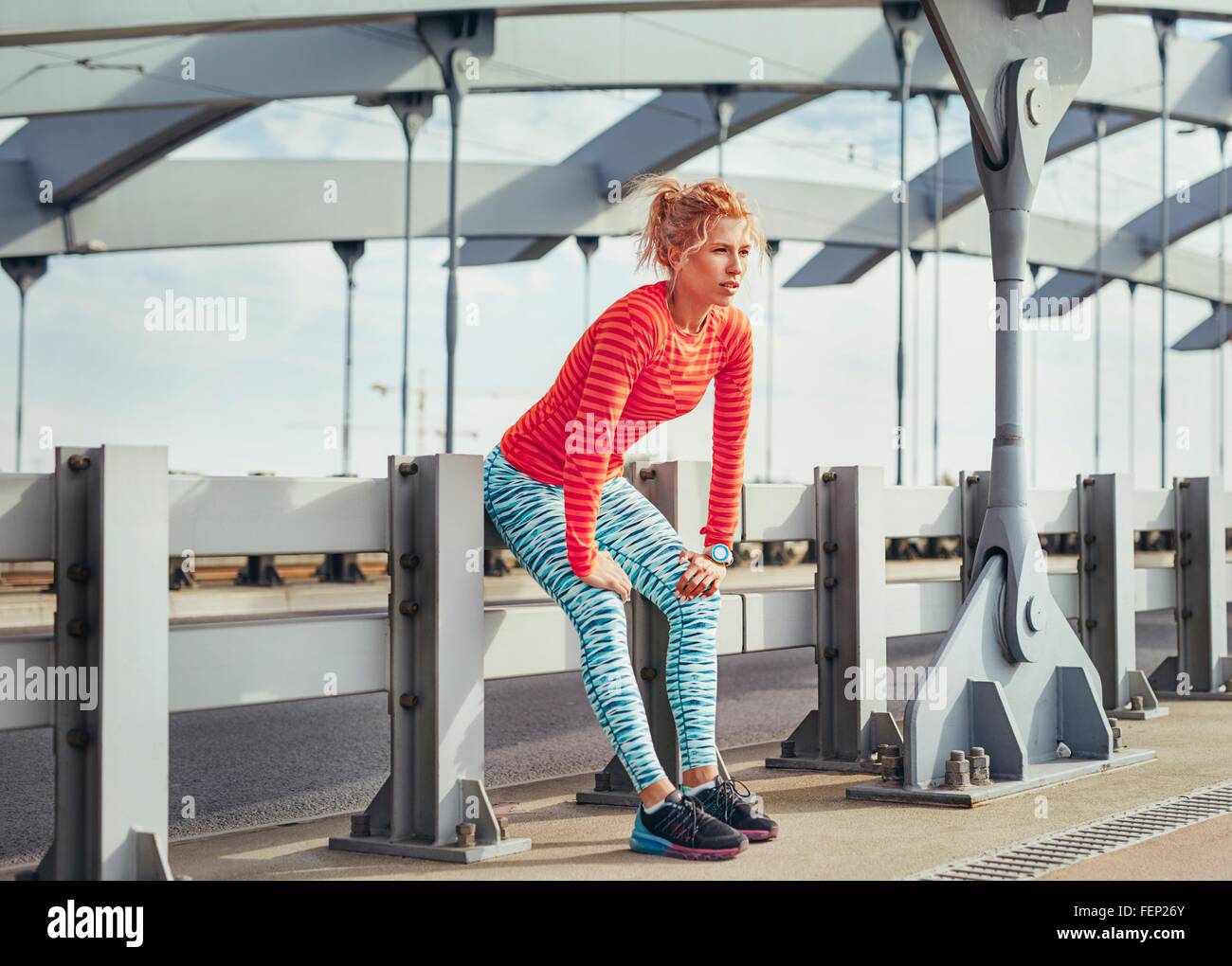 Young female runner taking a break on city footbridge fence Stock Photo ...
