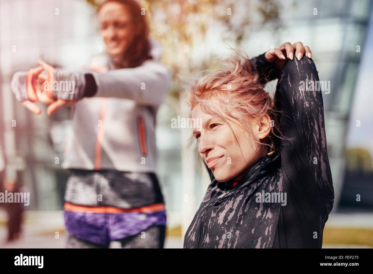 Two female runners stretching arms in city Stock Photo - Alamy