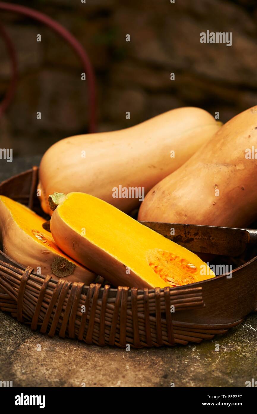 High angle view of halved and whole butternut squash in wick basket ...
