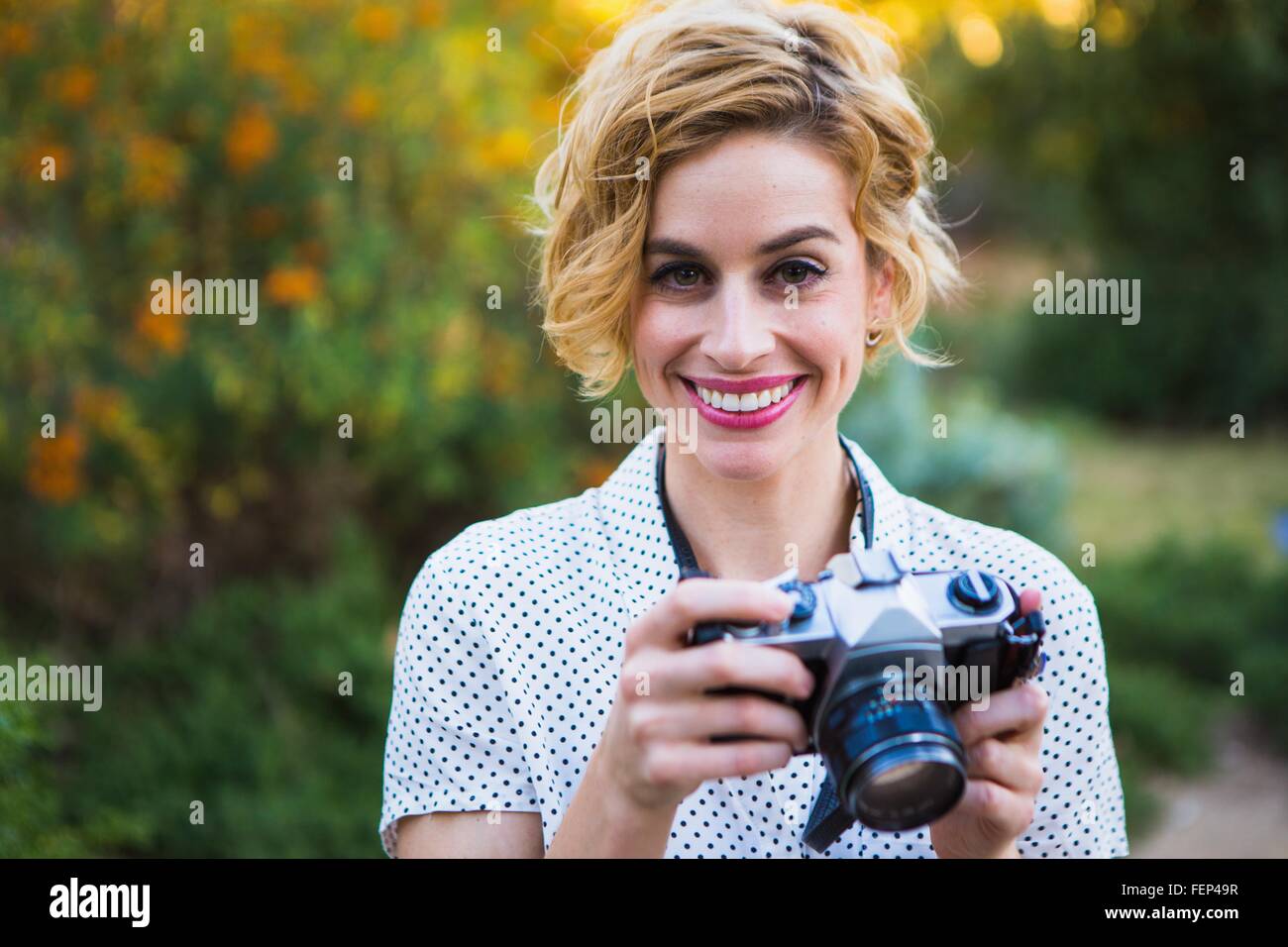 Portrait of mid adult woman holding SLR camera, smiling Stock Photo - Alamy