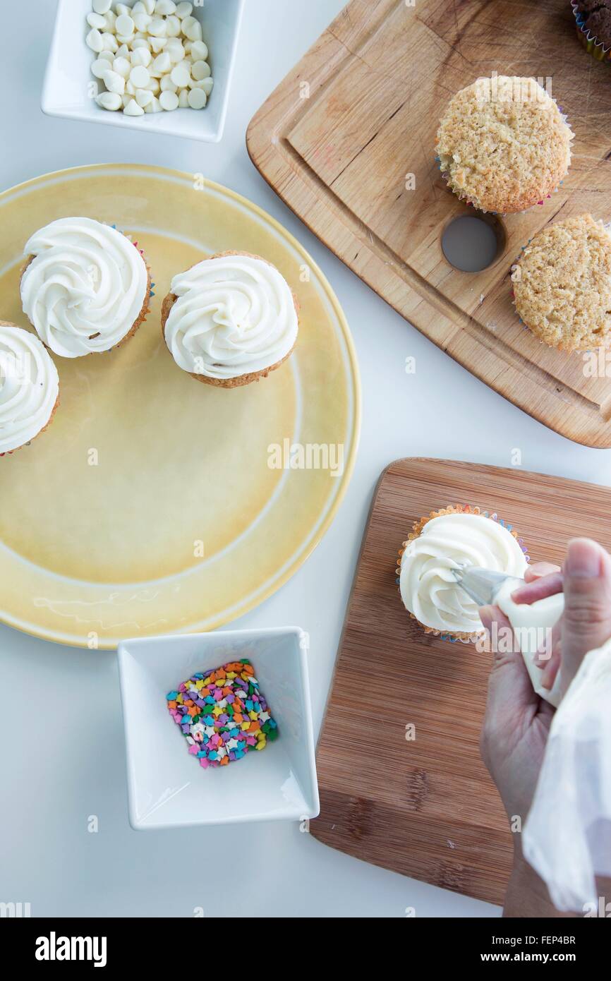 Overhead view of person icing cupcake Stock Photo - Alamy
