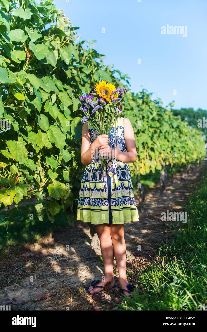 Girl holding bunch of flowers in front of face in vineyard Stock Photo ...