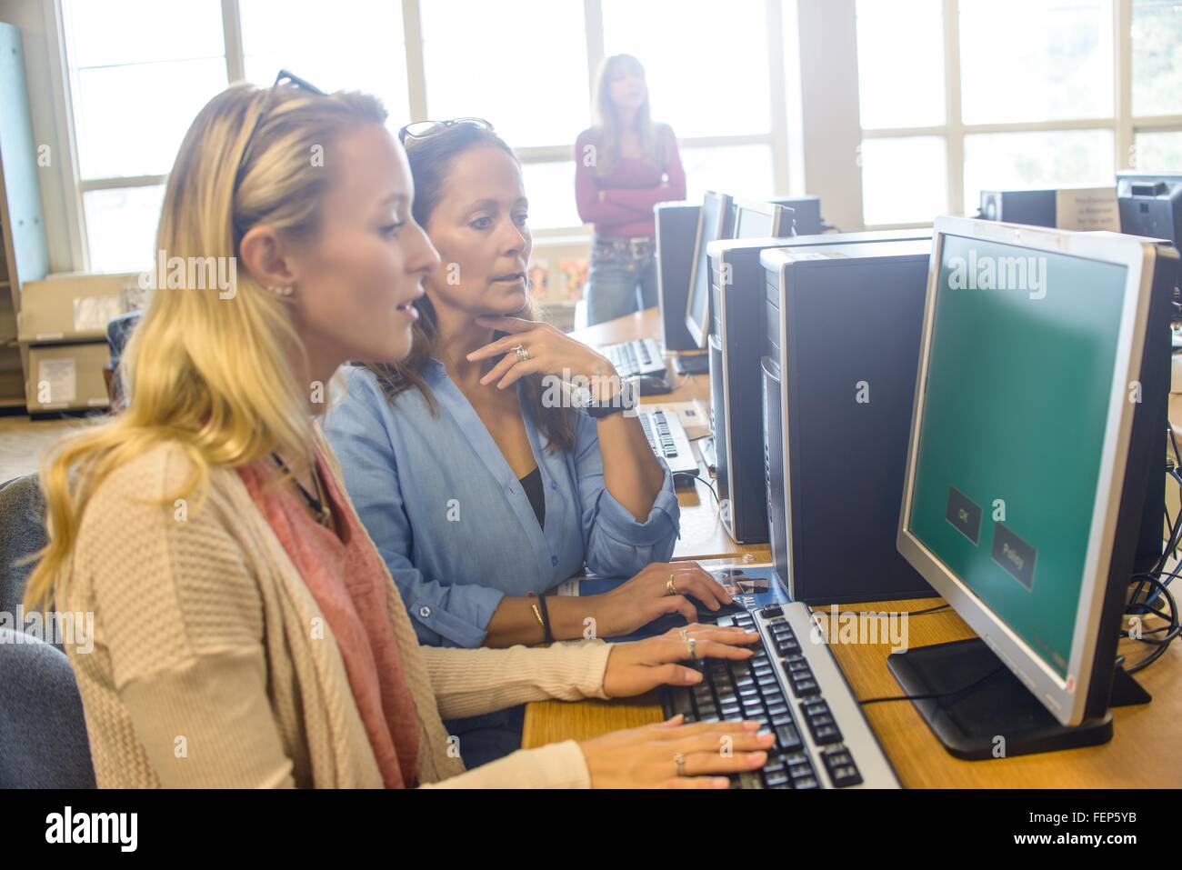 Two women searching computer data for books in library Stock Photo - Alamy