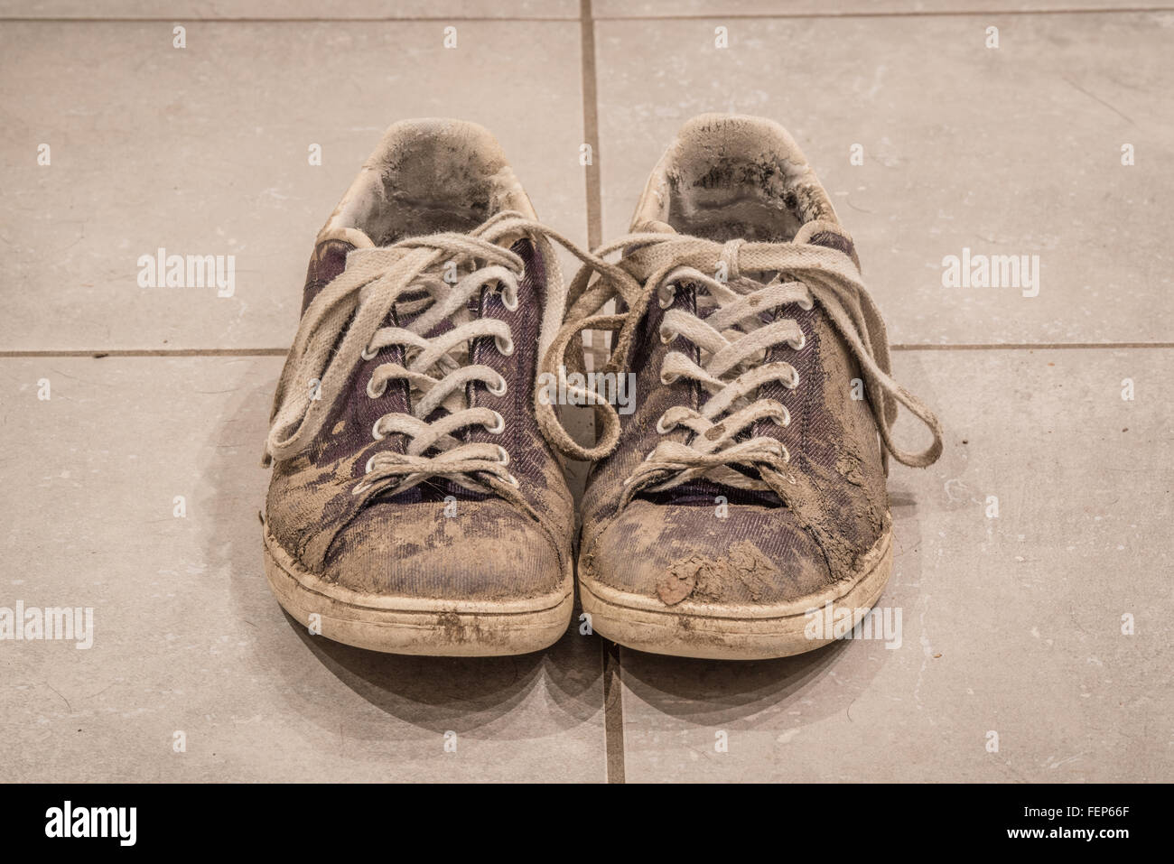 Pair of dirty shoes with mud on the floor Stock Photo - Alamy