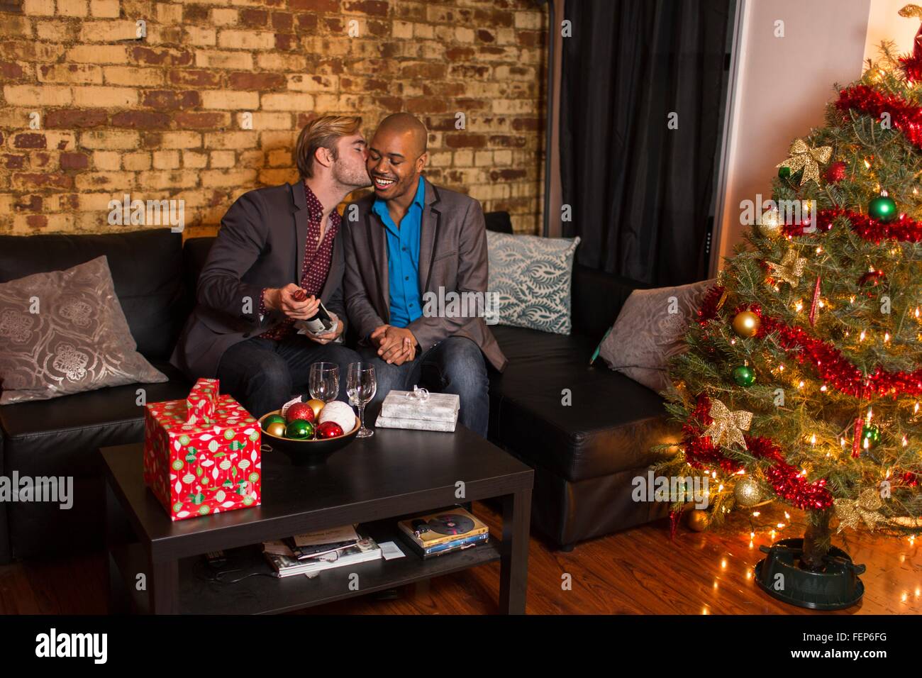 Male couple celebrating Christmas, young man giving partner a kiss ...
