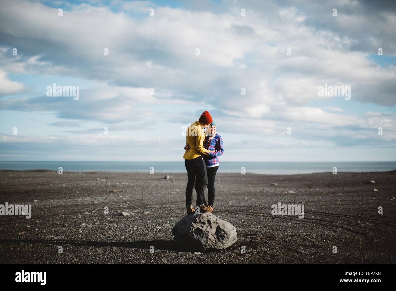 Mid adult couple standing on top of boulder, face to face hugging on ...