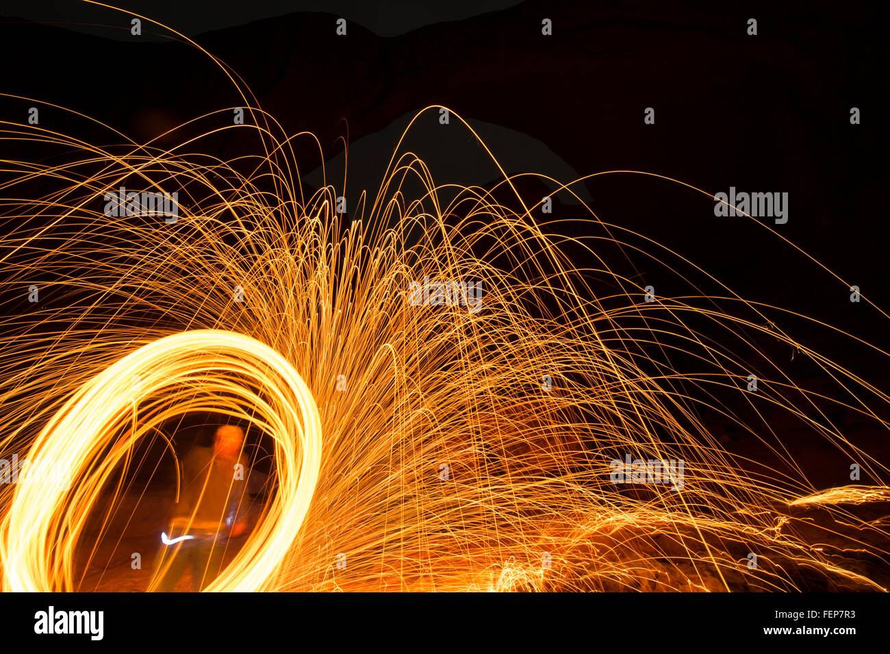 One person creating yellow circular light trails and sparks at night ...