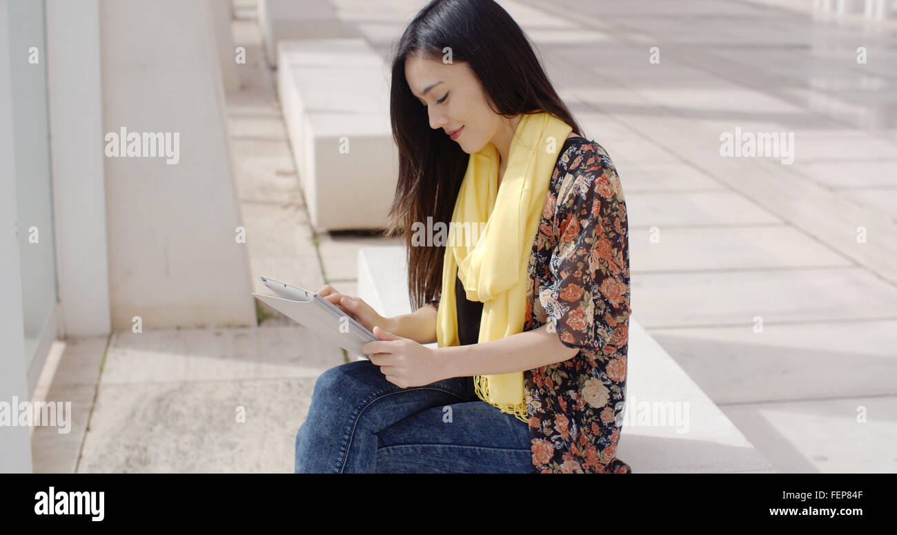 Young woman sitting reading her tablet Stock Photo - Alamy