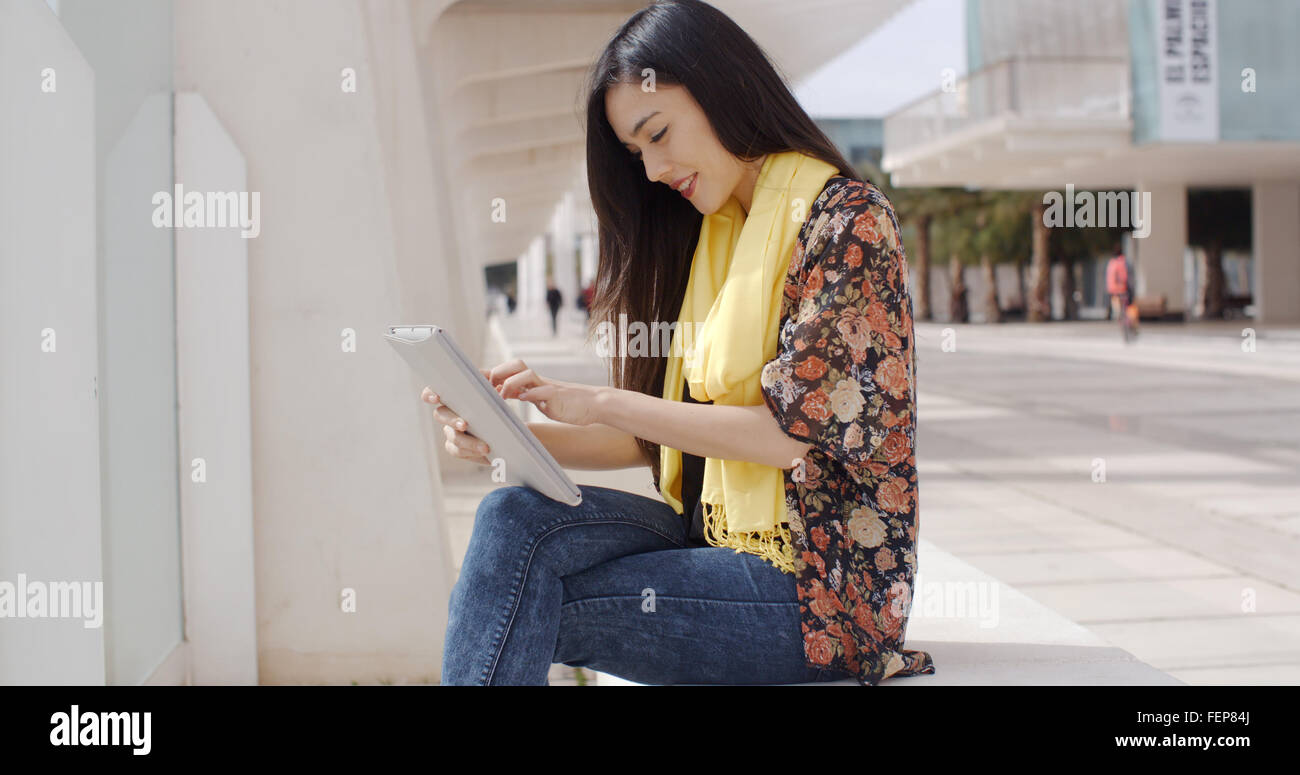 Young woman sitting reading her tablet Stock Photo - Alamy