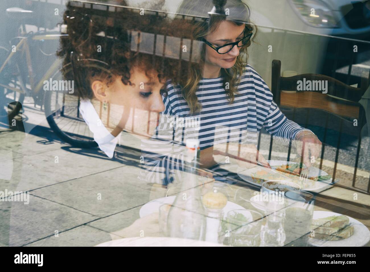 Cafe window view of two women eating lunch Stock Photo - Alamy