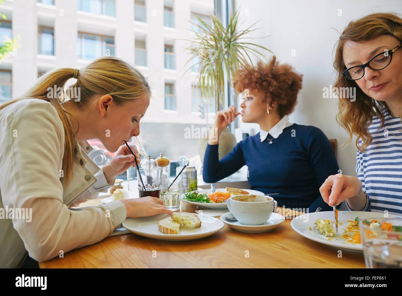 Three women eating salad lunch in cafe Stock Photo - Alamy