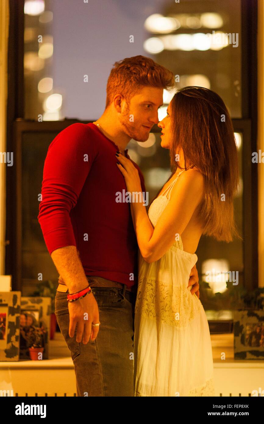 Side view of couple in apartment standing face to face hugging Stock ...