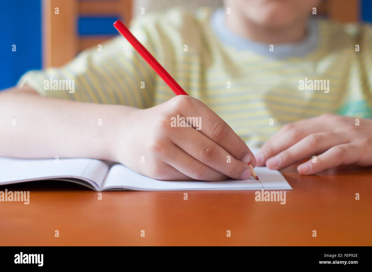 Boy writes his homework with red pencil Stock Photo - Alamy