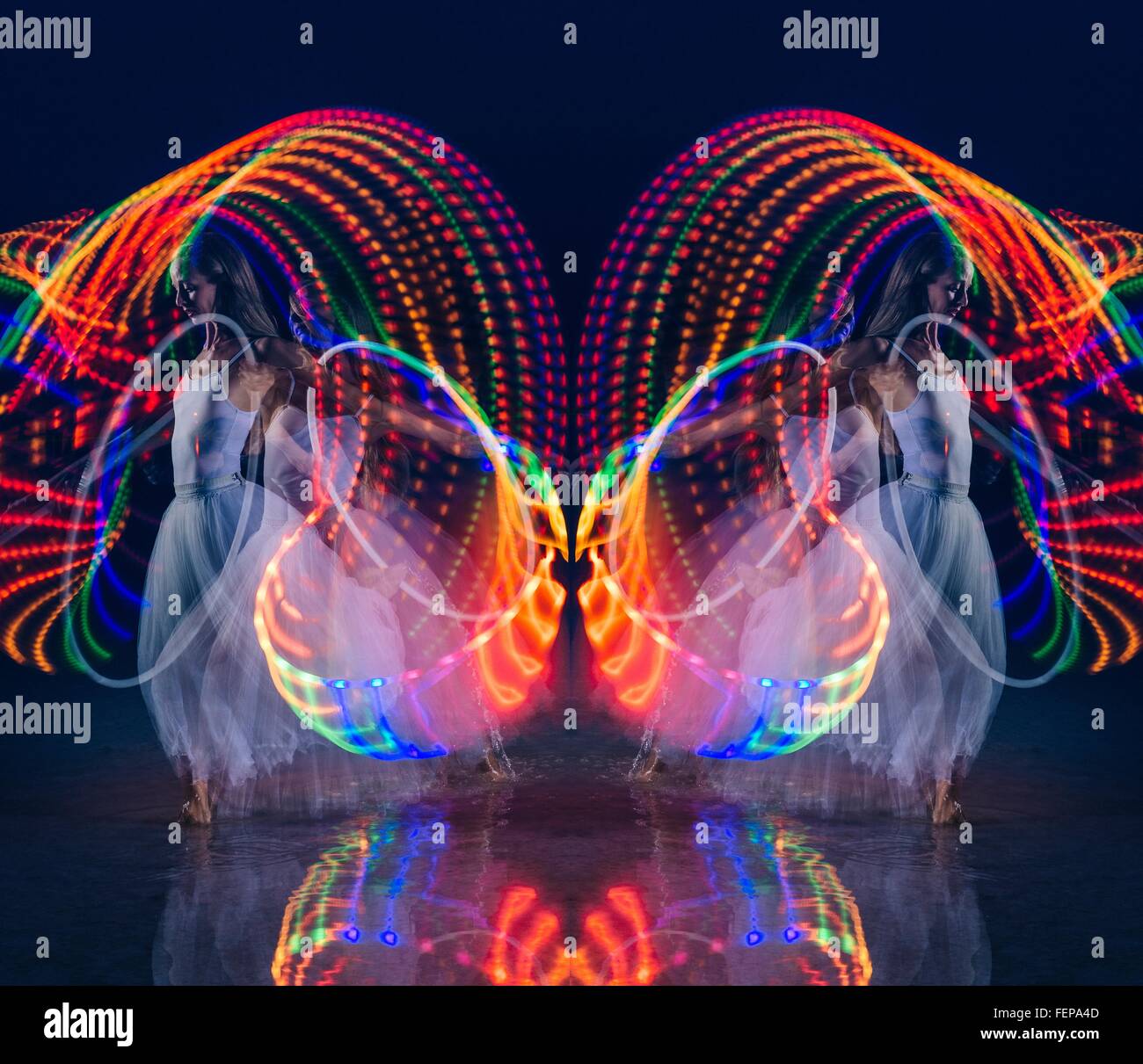 Symmetrical composite of woman dancing with illuminated multi-coloured ...