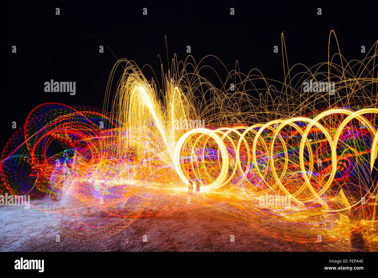 Woman creating yellow circular light trails with sparkler at night ...