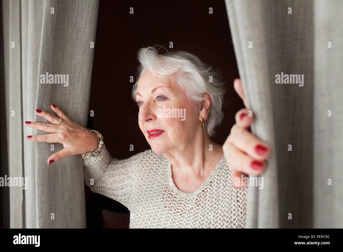 Senior woman, opening curtains Stock Photo - Alamy