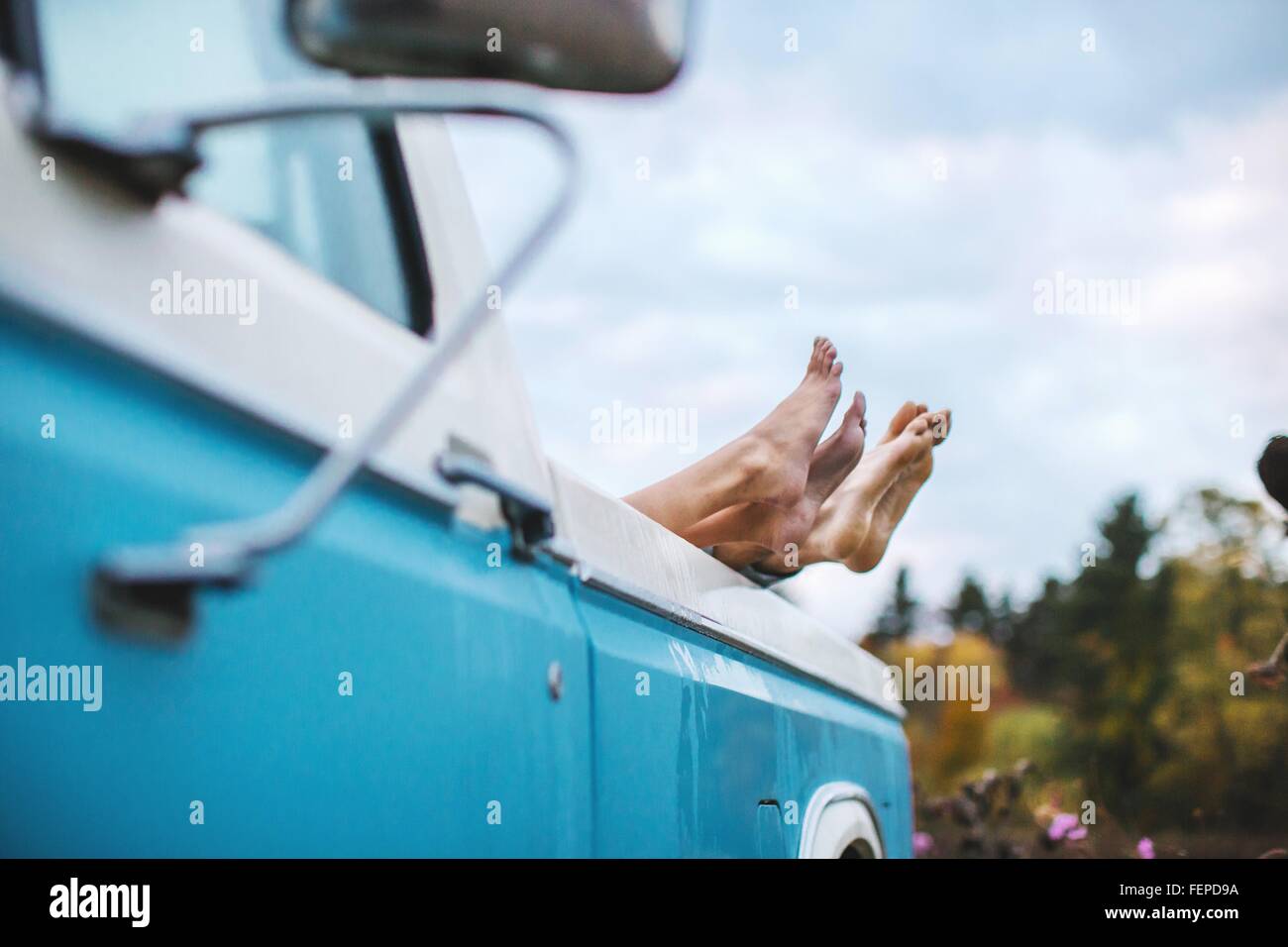 Young couple lying in back of truck, bare feet on edge of truck, focus ...