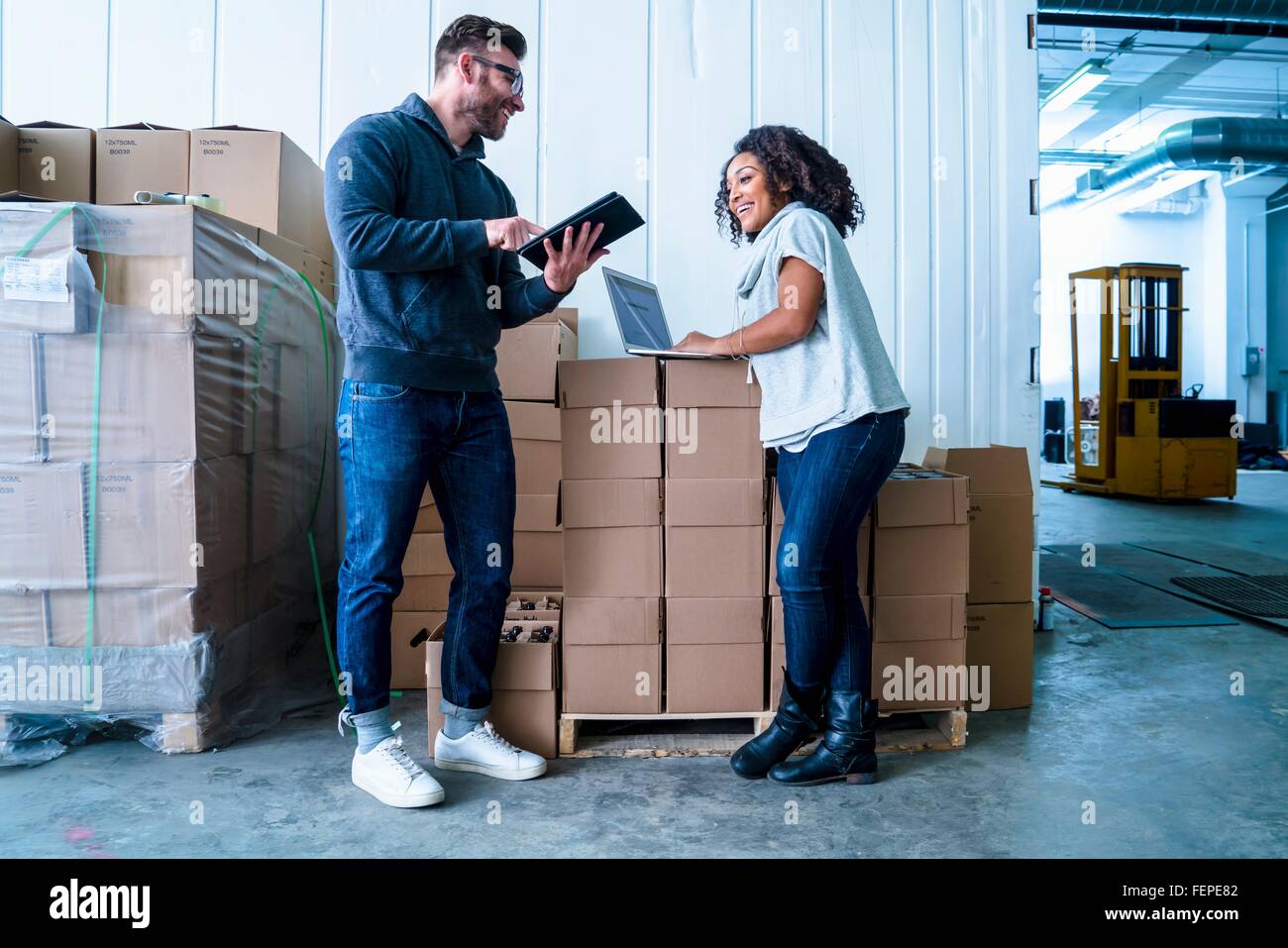 Full length view of colleagues in warehouse looking at digital tablet ...
