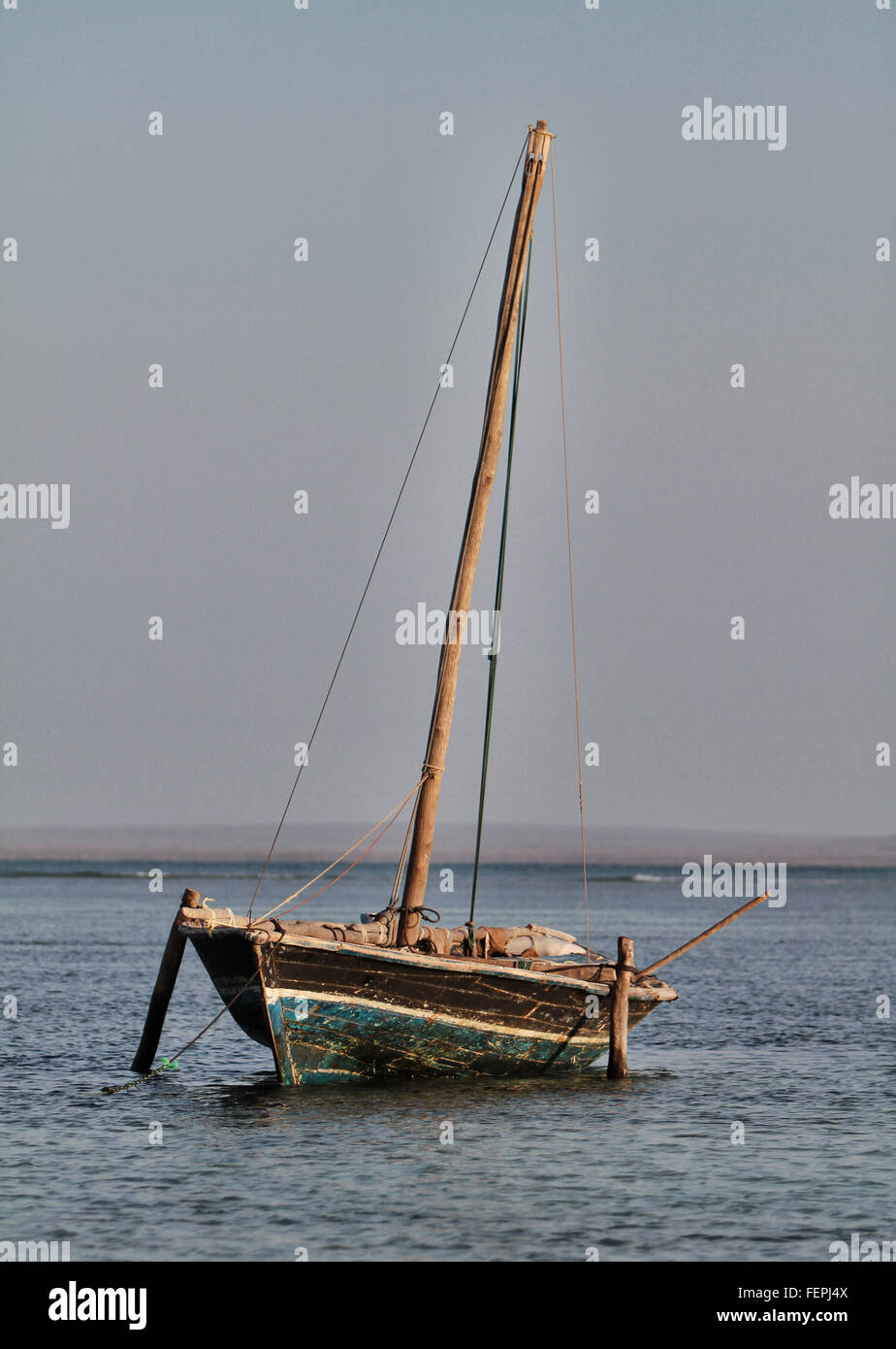 A traditional dhow or tribal sailing boat is anchored in the bay of ...