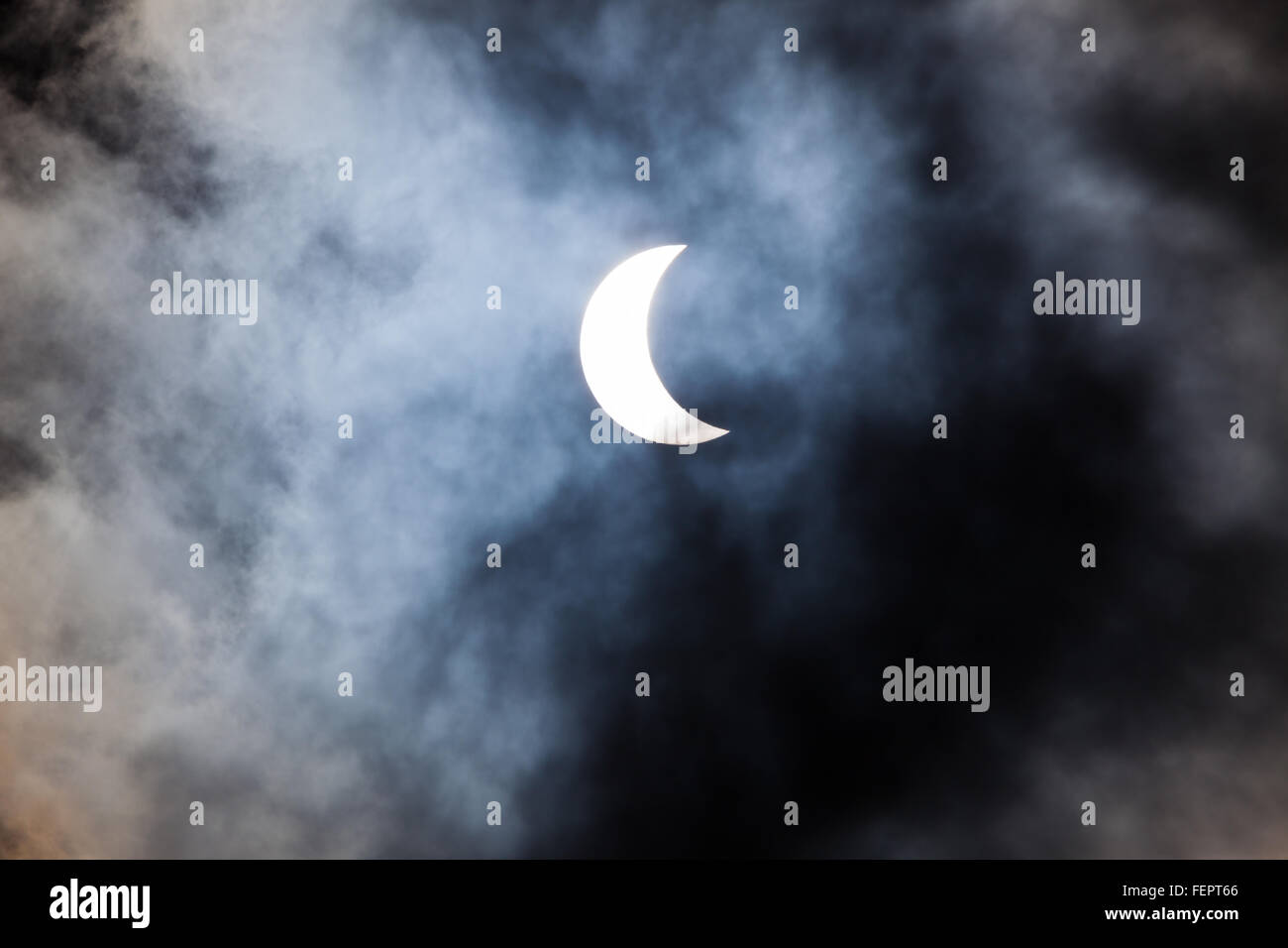 Partial solar eclipse through clouds Stock Photo - Alamy