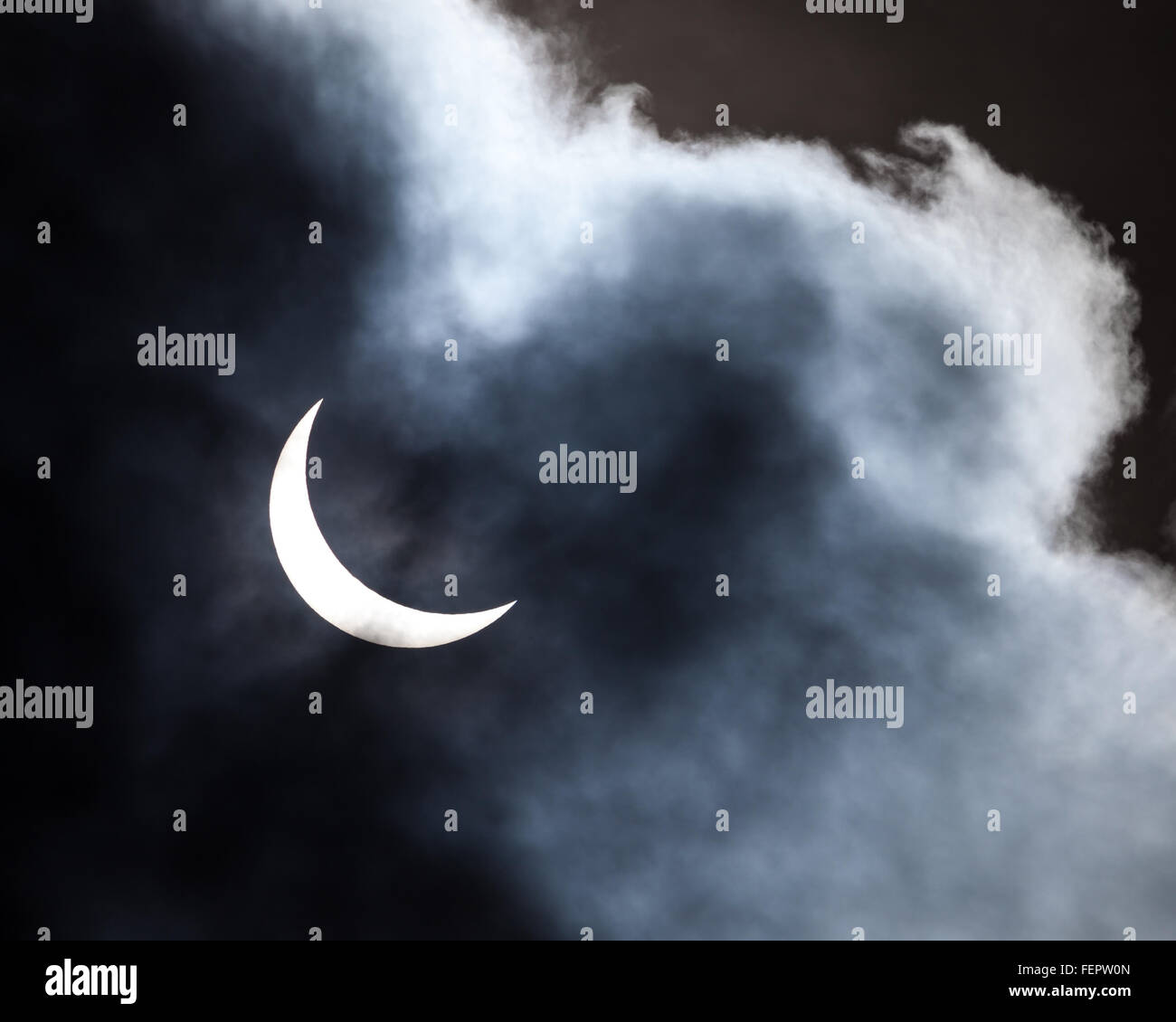 Partial solar eclipse through clouds Stock Photo - Alamy