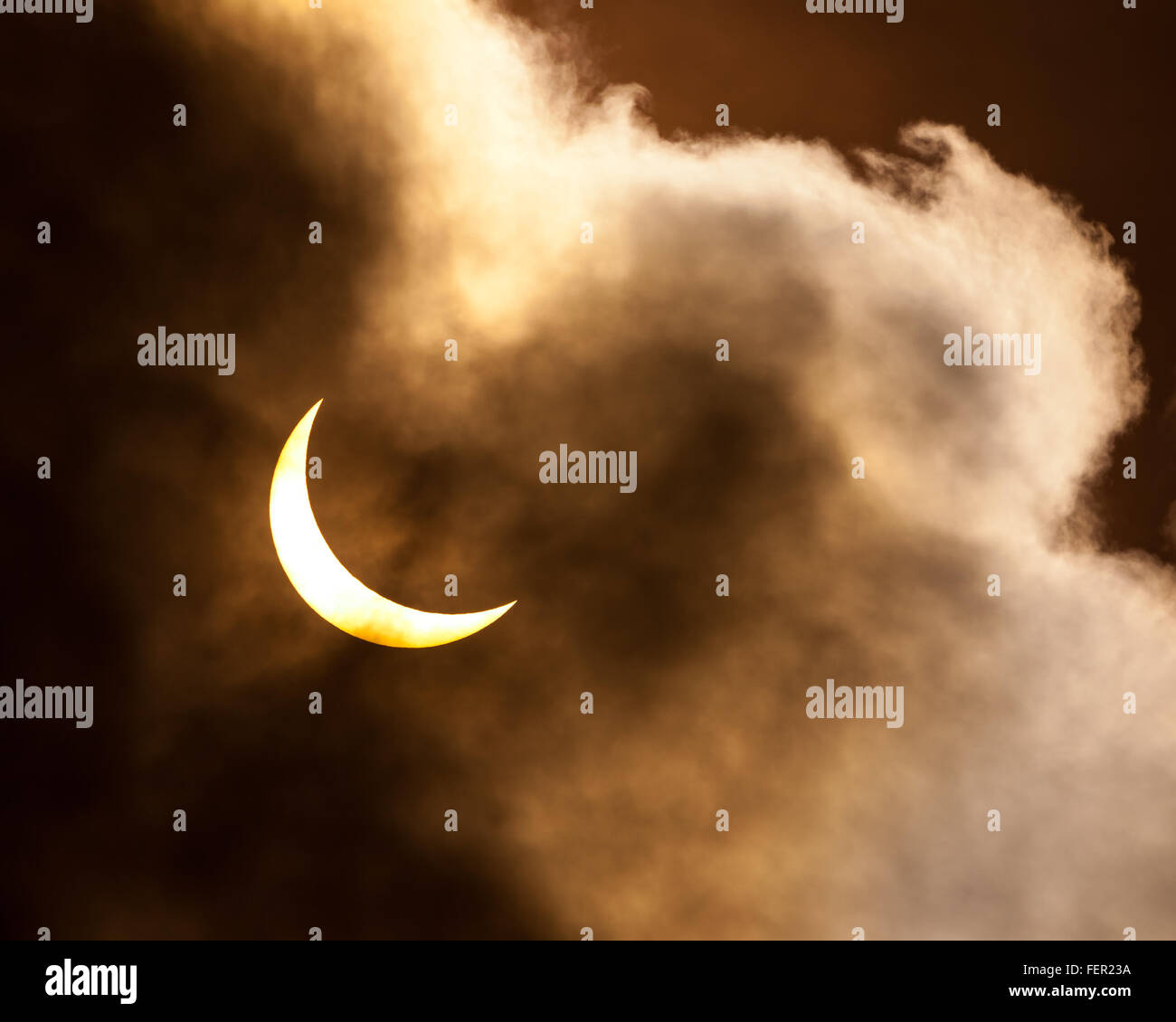 Partial solar eclipse through clouds Stock Photo - Alamy
