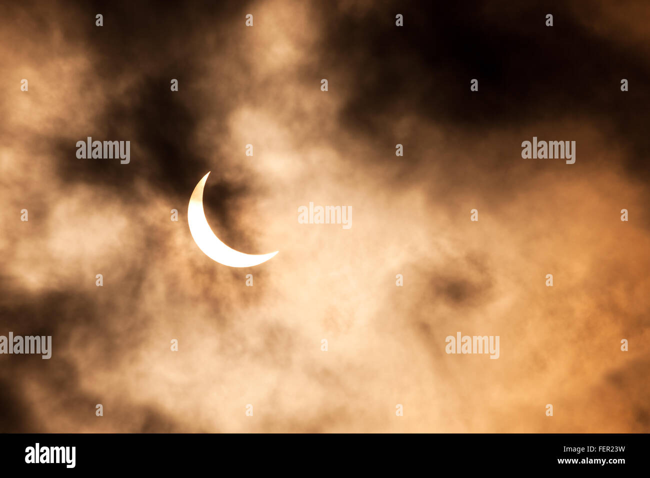 Partial solar eclipse through clouds Stock Photo - Alamy
