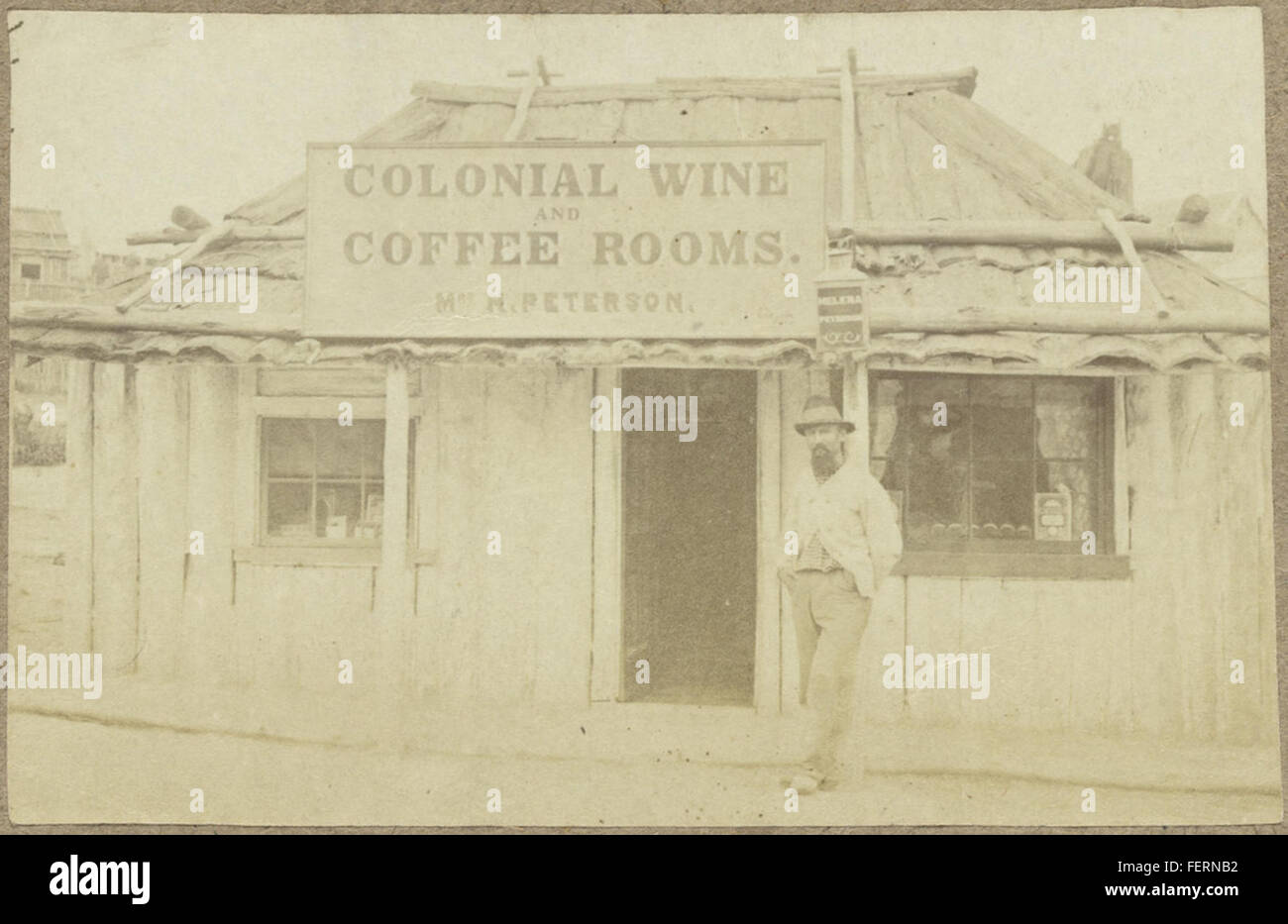 Man standing outside Mrs H Peterson's Colonial Wine and Coffee Stock ...