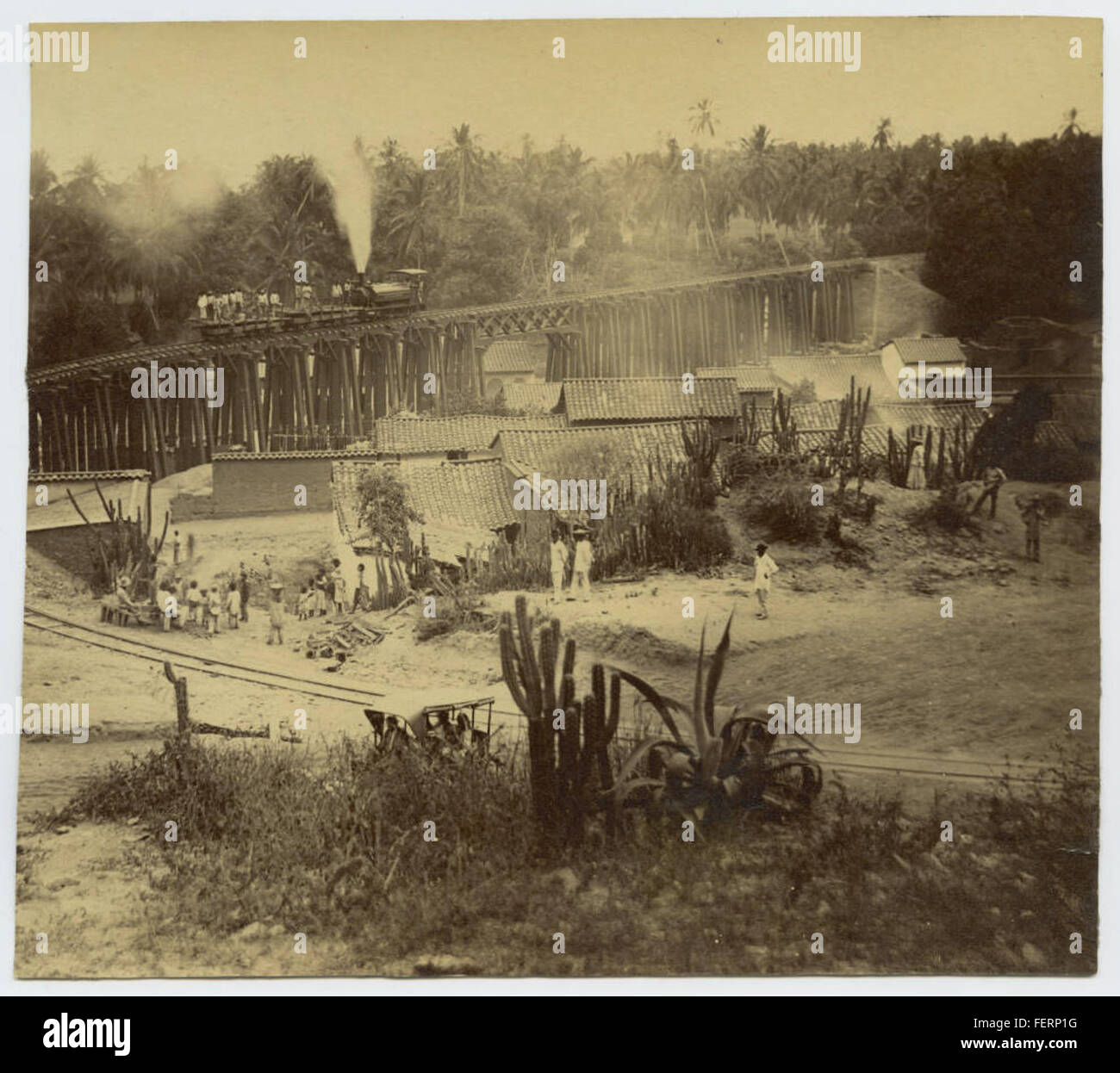 A photograph of workers on a railroad bridge with a locomotive passing ...